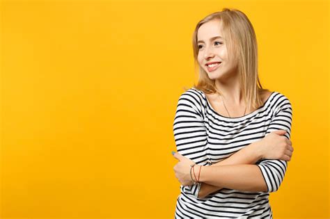 옆으로 보이는 줄무늬 옷에 웃는 젊은 여자의 초상화 손을 잡고 스튜디오에서 노란색 주황색 배경에 고립 된 교차 사람들은 진심으로 감정 라이프 스타일 개념입니다 복사 공간을