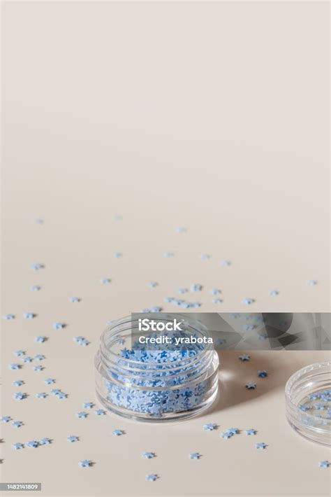 손톱 장식을 위한 요소 네일 액세서리 상자의 파란색 별 베이지색 배경에 유리 항아리에 있는 네일 아트용 별 복사 공간 창조적 인 아름다움 개념 파스텔 색상 사진 시각적