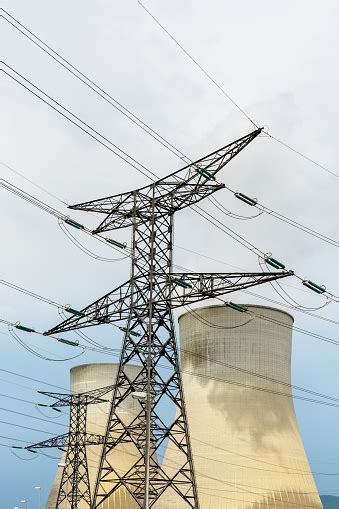 수증기의 구름을 발표 하는 배경에서 원자력 발전소의 2 개의 냉각 타워와 높은 전압 오버 헤드 전원 라인을 지 원하는 송신 탑의 낮은 각도 보기 강철에 대한 스톡 사진 및