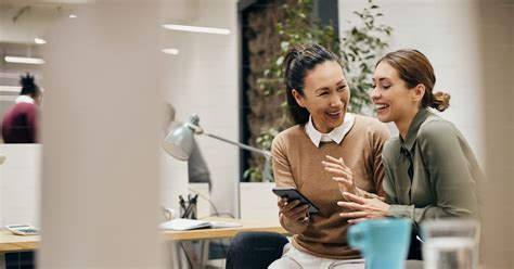 행복한 아시아 사업가와 그녀의 여성 동료는 사무실에서 휴대 전화를 사용하면서 재미 있고 웃고 있습니다 사진 Unsplash의 세르비아 이미지