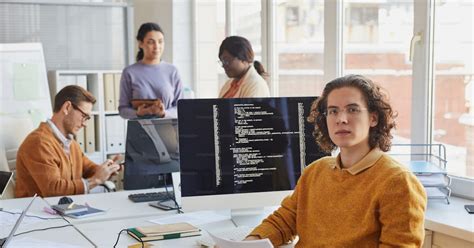 젊은 It 개발자가 소프트웨어를 제작하는 스튜디오에서 화면에 코드가 있는 컴퓨터에 대고 포즈를 취하는 동안 카메라를 바라보는 초상화 복사 공간 사진 Unsplash의