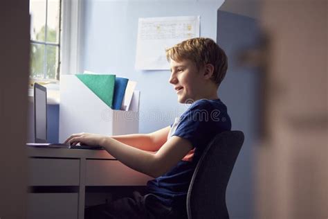 мальчик сидящий за партой обучается на ноутбуке на домашнем обучении во время пандемии