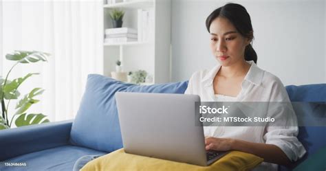 집에서 거실에서 소파에 앉아있는 동안 노트북에서 일하는 젊은 아시아 여성 가정 생활에 대한 스톡 사진 및 기타 이미지 가정 생활 거실 검색 Istock