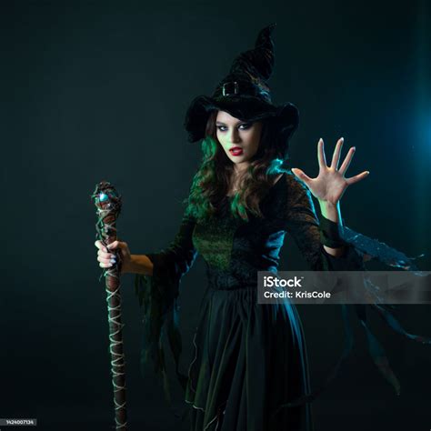 스태프와 함께 한 마녀가 주문을 보냅니다 검은 드레스와 뾰족한 모자를 입은 젊은 마녀 하이킹 지팡이에 대한 스톡 사진 및 기타 이미지 하이킹 지팡이 마법사 10월