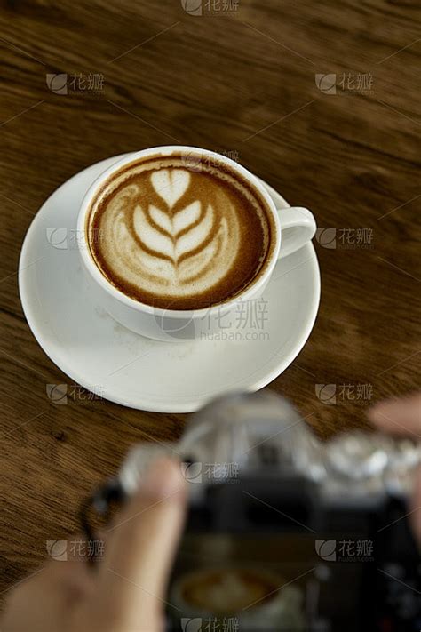 木质背景上的白色杯子上有心形图案的咖啡