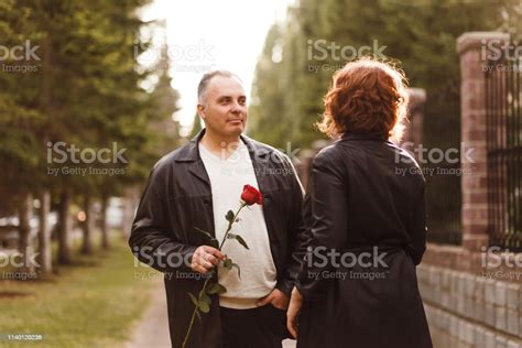 검은 자 켓에 있는 남자가 여자에 게 빨간 장미를 제공 합니다 중 년의 남편과 아내에서 여름에 일몰 25주년 결혼 기념에 대한 스톡 사진 및 기타 이미지 Istock