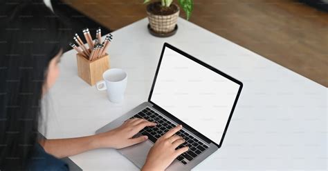 사무실의 흰색 책상에 흰색 화면이 있는 모형 노트북으로 작업하는 젊은 여성의 잘린 샷 사진 Unsplash의 태국 이미지