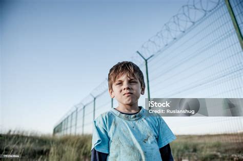 가시 면도기 철사와 푸른 하늘 울타리와 국가 국경 근처 슬픈 얼굴더러운 옷을 입고 전쟁 충돌 가난한 고아 난민 죄수 이주 아이의 피해자의 초상화 아이에 대한 스톡 사진 및
