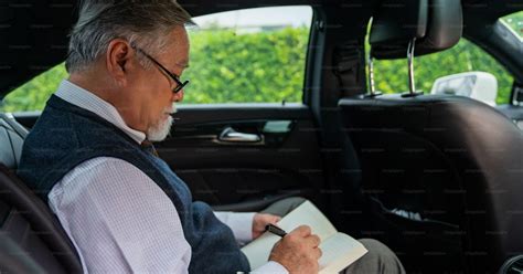자신감 있는 수석 사업가 Ceo는 안경을 쓰고 자동차 뒷좌석에 앉아 사무실로 출근하는 동안 책에 사업 계획을 씁니다 노인 사업가와 교통 개념 사진 Unsplash의