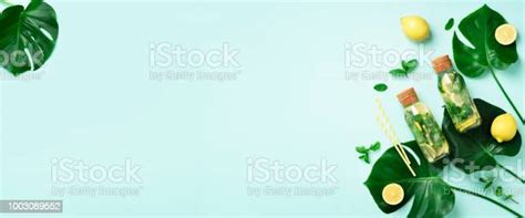민트 레몬 및 열 대 Monstera 해독 물 병 파란색 배경에 나뭇잎 플랫이 하다 배너입니다 감귤 류의 레모네이드입니다 여름 과일 물 주입 복사 공간 평면도 0명에 대한