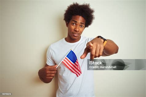 카메라와 당신에 게 손가락으로 가리키는 고립 된 흰색 배경 위에 서 미국 국기의 미국 부동산을 들고 아프로 남자 손 기호 앞에서 긍정적이 고 자신감 제스처 가리키기에 대한