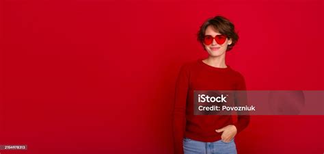 빨간 밝은 벽에 고립 된 하트 모양의 안경을 쓴 귀엽고 자신감 있는 트렌디 한 착용 여성의 배너 이미지 좋은 기분과 사랑의 감정을 가진 소녀 25 29세에 대한 스톡 사진