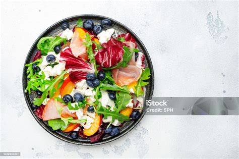 Arugula Radiccio 복숭아 훈제 돼지 고기 햄 페타 치즈 및 블루 베리를 곁들인 신선한 샐러드 흰색 테이블 배경 위쪽 보기 샐러드에 대한 스톡 사진 및 기타