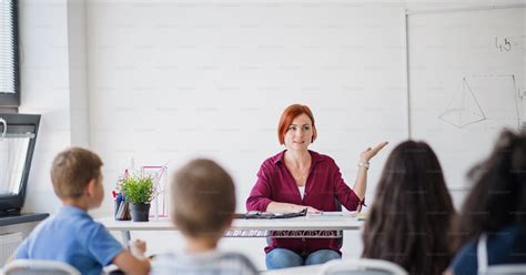 수업 시간에 교실 책상에 앉아 교사의 말을 듣고 있는 학교 아이들의 뒷모습 사진 Unsplash의 선생 이미지