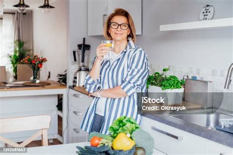 물을 마시는 건강한 습관 부엌에 레몬을 들고 순수한 물 한 잔을 들고 미소 짓는 중년 여성 제어 바디 수분 공급 수질 추적 건강한 생활 Selectivbe 초점 식수에 대한