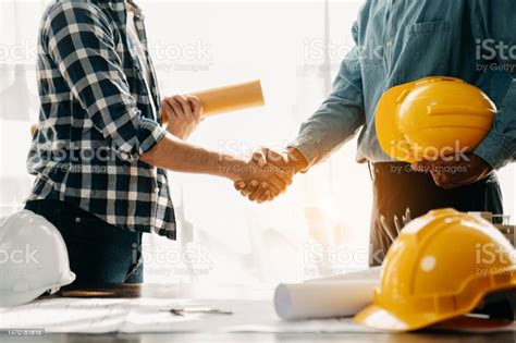 건설 팀은 건물 프로젝트에 대해 상담하기 위해 사무실 센터의 책상에 있는 노란색 헬멧 뒤에 새로운 프로젝트 계획을 시작하는