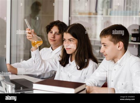 chemistry lesson schoolgirl and classmates holds flask for experiments