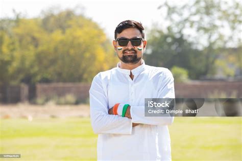 전통적인 하얀 드레스와 선글라스를 쓴 젊은 인도 남자의 초상화 쿠르타 삼색 핸드밴드가 공원에서 팔짱을 끼고 서 있다 독립 기념일 또는 공화국의 날을 축하합니다 인도 문화에