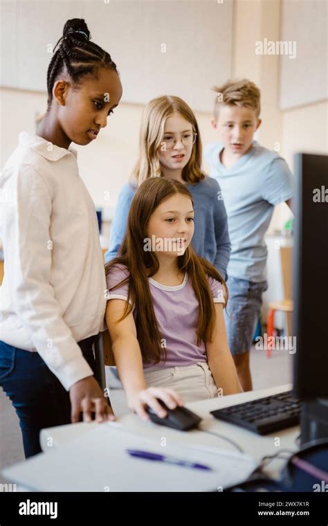 Girl Using Computer While Sitting Amidst Male And Female Pupils In Classroom Stock Photo Alamy