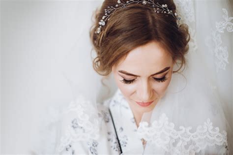 아름 다운 행복 한 신부 초상화 웃 고 아래를 내려다 보면서 그녀의 럭셔리 웨딩 드레스에 실크 가운에서 서 행복 한 순간입니다 결혼 개념입니다 아침에 준비 하는 신부