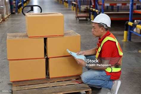 Saftyhat 및 반사 재킷 체크리스트를 가진 창고 작업자 남자 또는 소매 창고 물류 유통 센터의 생산 재고 및 재고로 배달하기 위한 대형 상자 패키지를 제어합니다 30