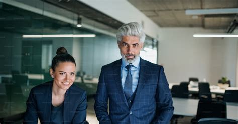 컴퓨터를 들고 사무실에 서서 카메라를 바라보는 두 사업가 사진 Unsplash의 테이블 이미지