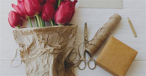 흰색 나무 배경에 인사말 카드 선물 연필 가위가 있는 공예 종이에 아름다운 빨간 튤립 소박한 인사말 카드 템플릿입니다 행복한 어머니의 날 행복한 여성의 날 사진