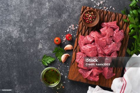 생 다진 쇠고기 고기 생 유기농 고기 쇠고기 또는 양고기 향신료 어두운 회색 콘크리트 배경에 오래된 나무 보드에 허브 굴라쉬
