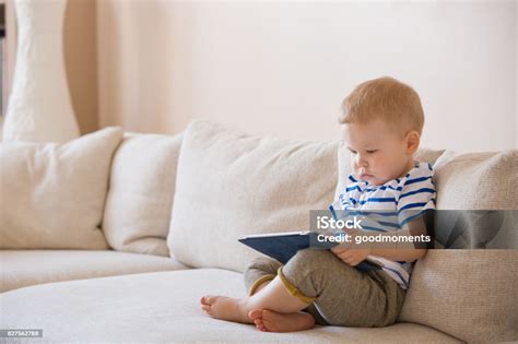 귀여운 금발 유아 소년 소파에 앉아서 태블릿 Pc와 놀이 집에서 실내 태블릿 컴퓨터와 아이입니다 화이트 아늑한 인테리어입니다 개념에 대한 스톡 사진 및 기타 이미지 Istock