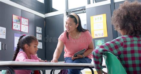In School Teacher Helping Students With Assignments At Classroom Table