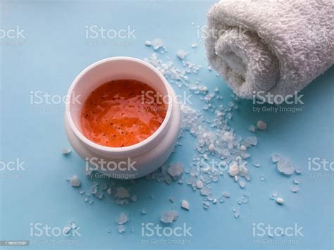 오렌지 스크럽 흰색 수건 항아리와 밝은 파란색 배경에 큰 목욕 소금 주위에 흩어져 스파 컨셉 바디 클렌징 및 보습 안티 셀룰