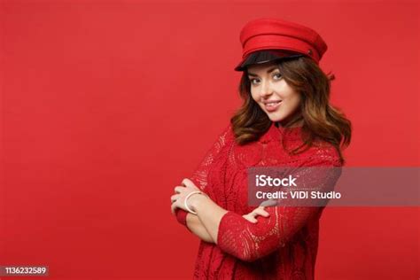 레이스 드레스에 매력적인 아름 다운 젊은 여자의 초상화 스튜디오에서 밝은 빨간색 벽 배경에 고립 된 손 접힌 모자를 들고 사람들은 진심으로 감정 라이프 스타일 개념입니다