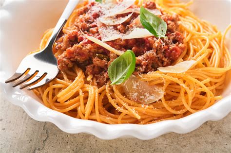 파스타 스파게티 볼로냐세 회색 돌 또는 콘크리트 테이블 배경에 흰색 접시에 볼로냐 소스 토마토 소스 치즈 파르 메산 및 바질과 함께 이탈리아 스파게티를 맛있게 식욕을 돋우는