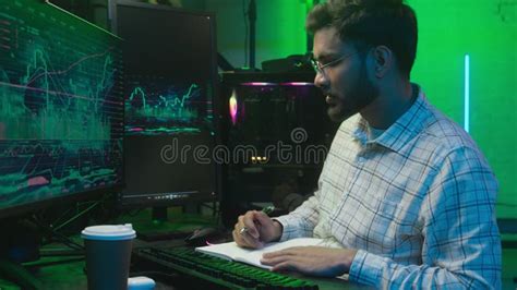 Indian Arabian Man Looking Monitor Computer Chart Graph Trading Online Typing Pc Writing Notes