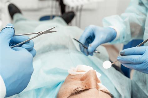 치과 의사는 수술 임플란트 배치를 수행합니다 실제 작동 치아 추출 임플란트 전문 유니폼 과 치과 의사의 장비 의사의 직장을 갖추는 의료 서비스 치과 거울에 대한 스톡 사진