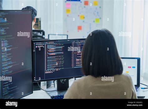 asian software developers working on multiple screens displaying code and application diagrams