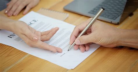 자동차 보험 증권에 서명하는 남자 에이전트가 문서를 가리키고 있습니다 사진 Unsplash의 금융 이미지