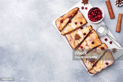 나무 스탠드에 가루 설탕을 뿌린 크랜베리와 향신료를 곁들인 코티지 치즈 파이 캐서롤 회색 콘크리트 테이블입니다 복사 공간 가루 설탕에 대한 스톡 사진 및 기타 이미지