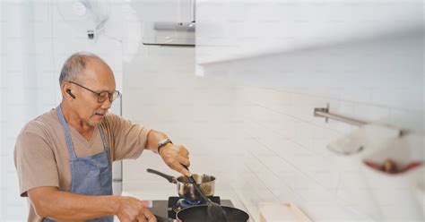 행복한 아시아인 성숙한 성인 남자가 안경을 쓰고 부엌에서 요리하고 음식을 준비합니다 사진 Unsplash의 휴식 이미지