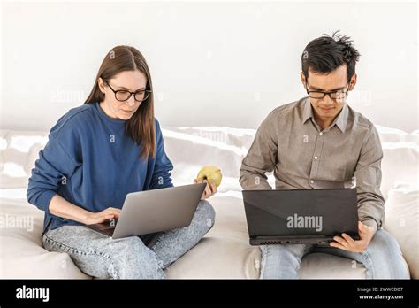 diverse programmers using laptops sitting on sofa at creative startup