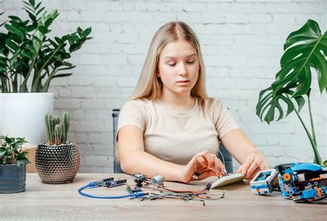 Premium Photo A Blonde Teen Girl Plugging Cables To Sensor Chips While Learning Arduino Coding