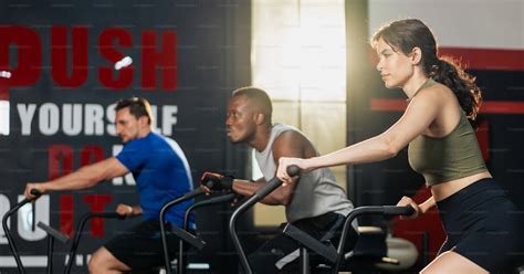 피트니스 체육관에서 함께 운동하는 젊은 운동 선수 그룹 매력적인 활동적인 스포츠맨과 여성들은 건강 관리와 경기장에서의 웰빙을 위해 자전거 기계에서 자전거를 타며 함께