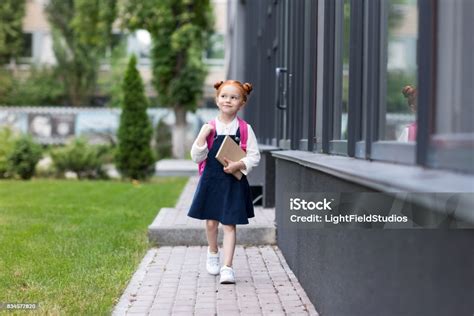 Linda Colegiala Pelirroja De Poco Sostiene Libro Y Caminar Cerca De La