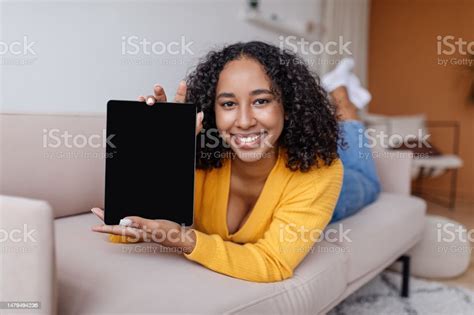 빈 화면이 있는 태블릿 컴퓨터를 보여주는 행복한 젊은 아프리카계 미국인 여성 집에서 소파에 누워 모형 16 17 살에 대한 스톡 사진 및 기타 이미지 Istock