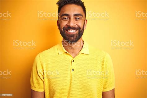 얼굴에 행복하고 시원한 미소와 고립 된 노란색 배경 위에 서 폴로를 입고 젊은 인도 남자 운이 좋은 사람 노랑에 대한 스톡 사진 및 기타 이미지 Istock