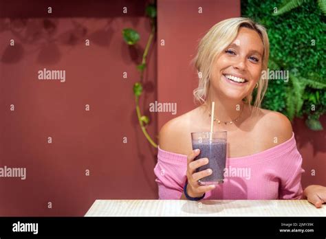 Young Woman Smiling At Camera While Enjoying Drinking A Delicious