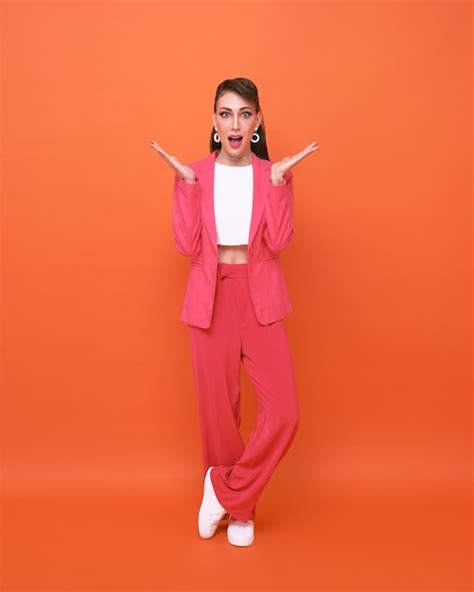 Удивленная молодая женщина на оранжевом фоне Бесплатно Фото