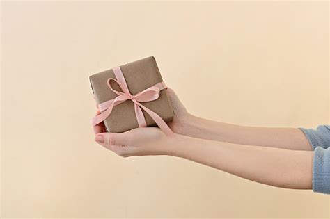 창백한 베이지 색 배경을 통해 분홍색 리본공예 종이에 싸여 선물 상자를 들고 여성 손 개념에 대한 스톡 사진 및 기타 이미지 개념 겨울 공예 Istock