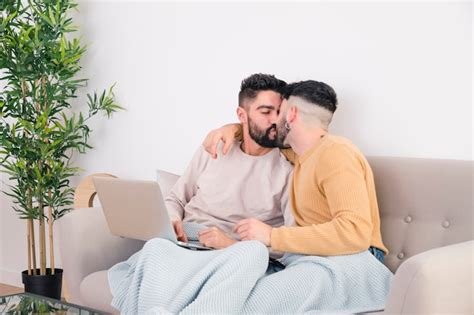 서로 키스하는 소파에 앉아 로맨틱 젊은 게이 커플 무료 사진