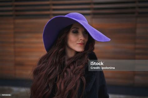 아름 다운 미소 매력적인 젊은 여성이 자외선 컬러 모자에 긴 머리를 가진 나무 벽 배경 이다 바람에서 물결치는 고급 스러운 갈색 머리입니다 시선은 아래로 이동 갈색에 대한